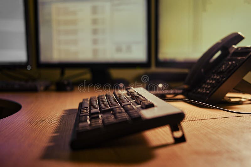 Computer Keyboard on an Office Desk with Monitors and a Phone, Close-up ...
