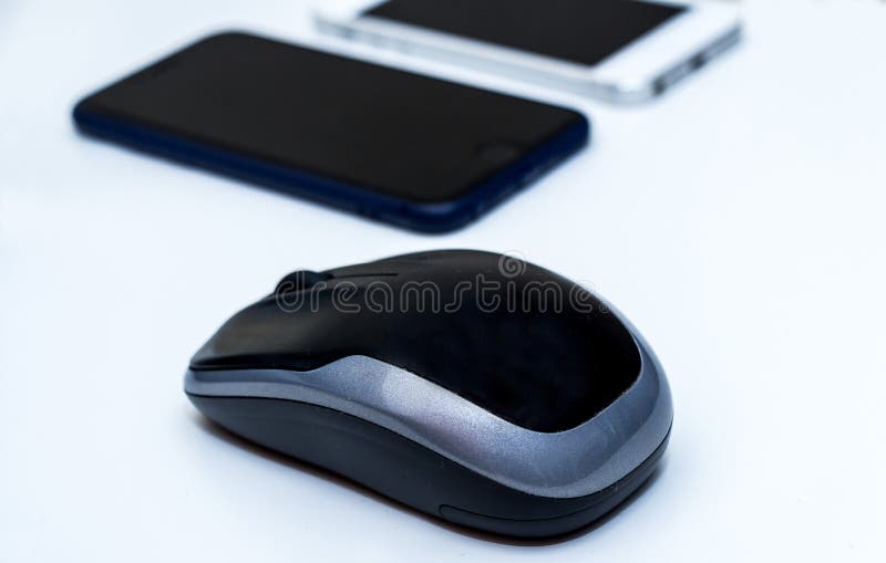 Computer Wireless Mouse and Two Mobile Phones on a White Desk. Stock ...