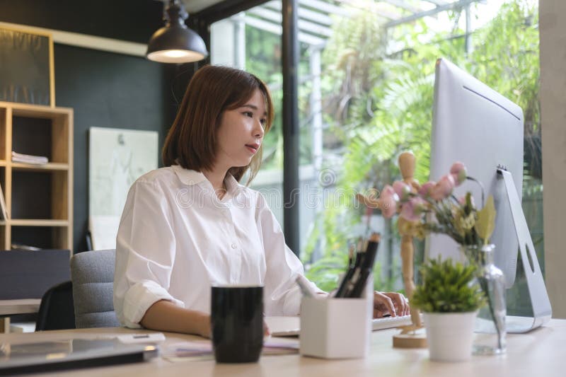 Concentrated Asian Female Office Worker Working with Computer at Modern ...