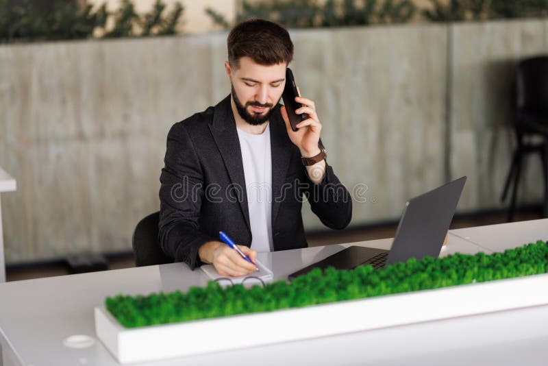 Concentrated Businessman Talking on Mobile Phone and Taking Notes in ...