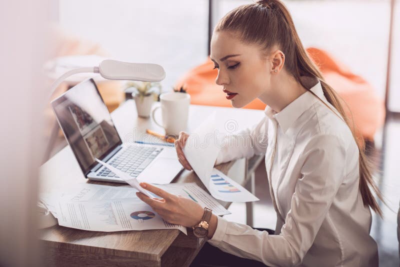 Concentrated Businesswoman Reading Documents and Sitting at Table in ...