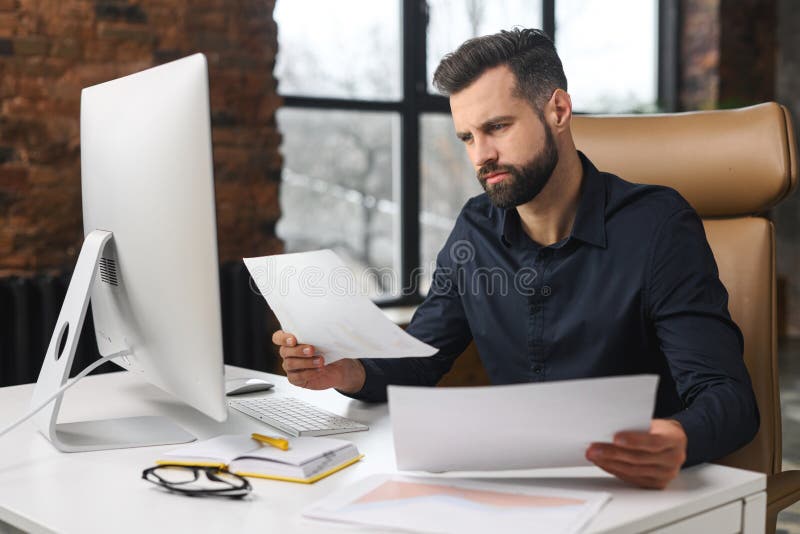 Concentrated Caucasian Guy is Doing Paperwork. Man Looking through ...