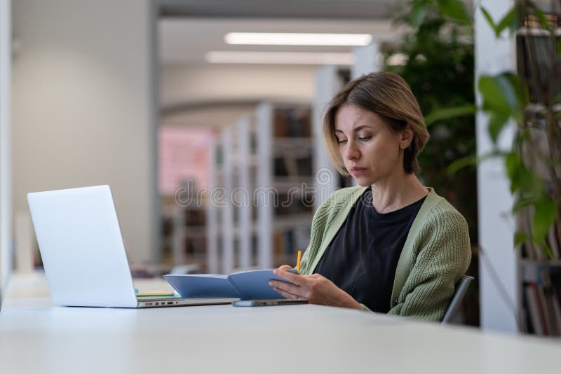 Concentrated Female University Professor Checking Course Schedule while ...