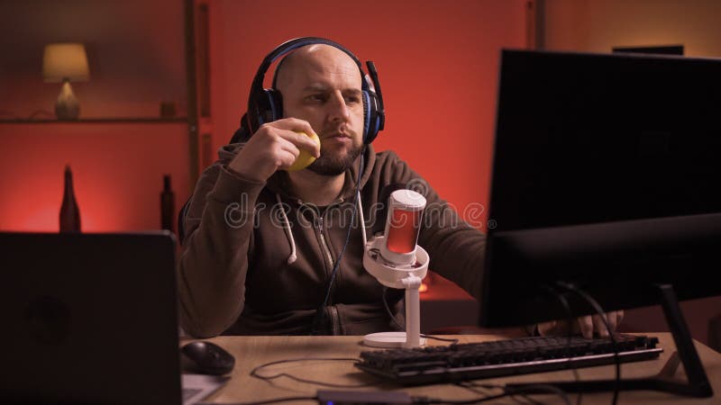Concentrated Gamer Playing Online Games on Computer and Eating Apple ...