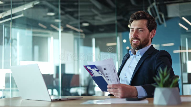 Concentrated Male Worker Browsing Internet with Travel Documents in ...