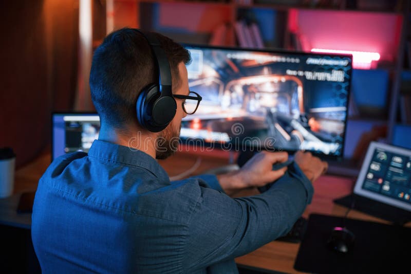 Concentrated Man is Playing the Shooter Game on His Computer. Neon ...