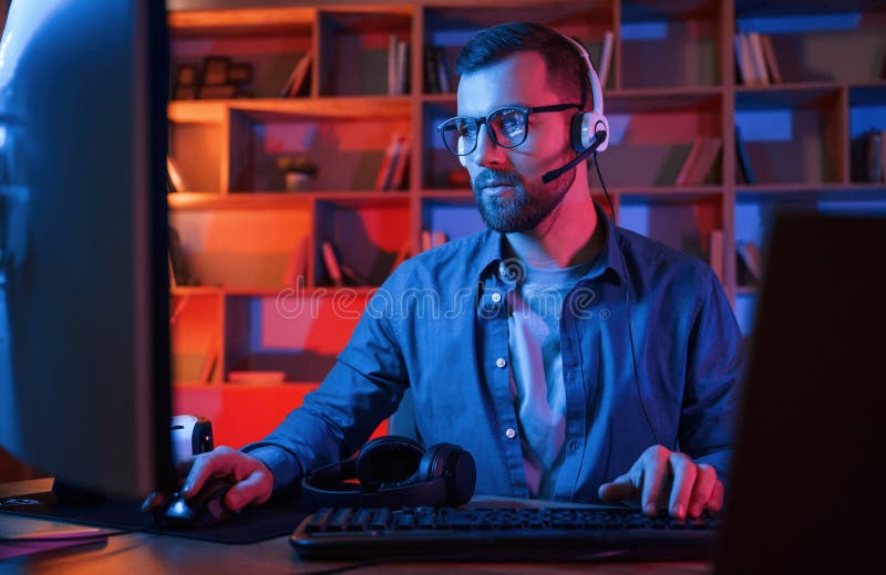 Concentrated Man is Sitting by a Computer Indoors at Home. Neon ...