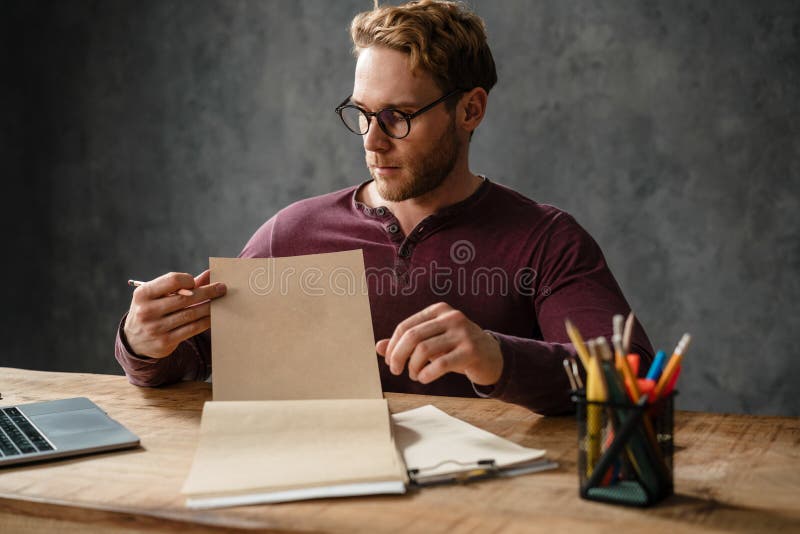 The Concentrated Man Sitting at the Table while Flipping through Papers ...