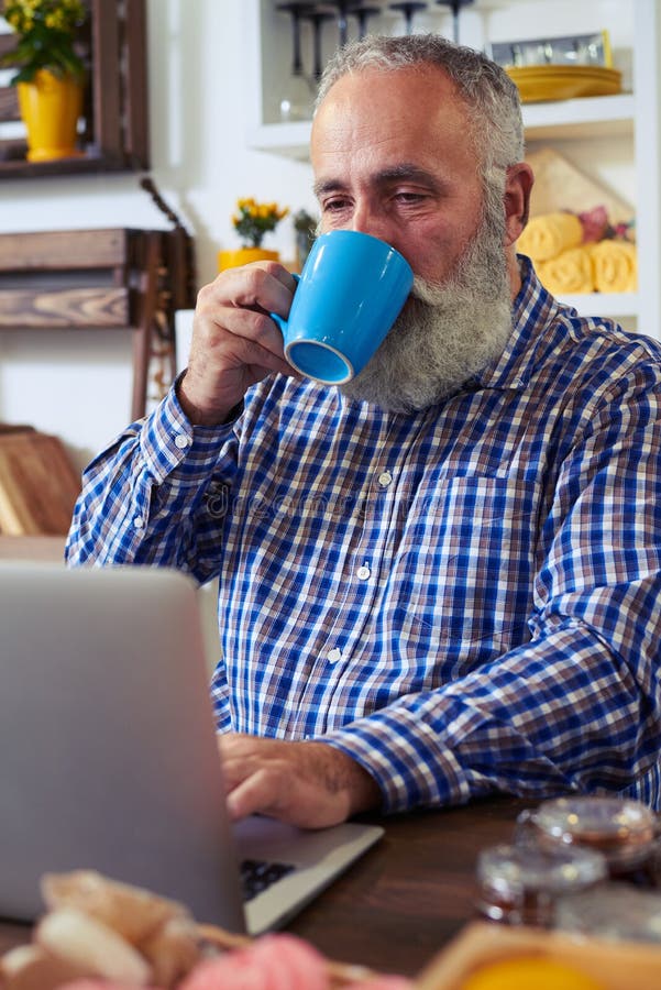 Concentrated Man Typing Something on the Laptop while Having a T Stock ...