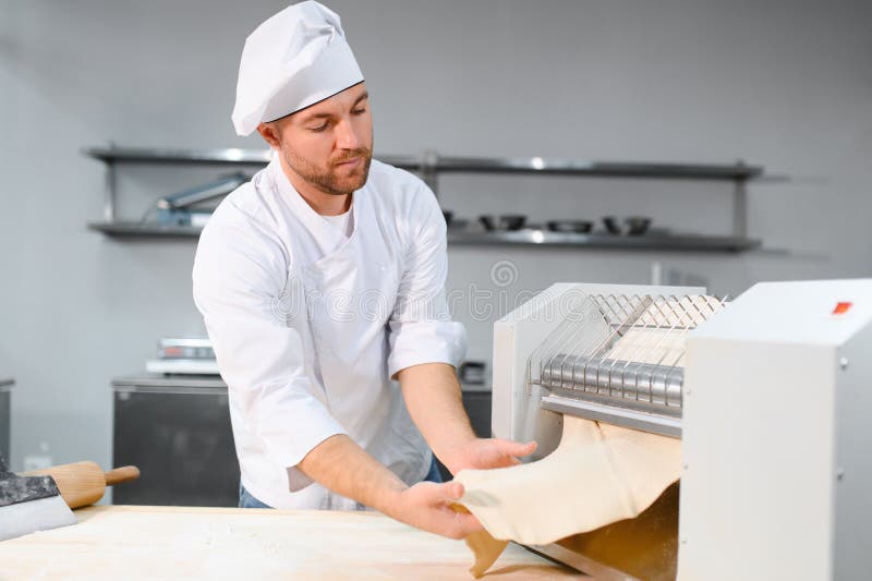 Concentrated at Work. Handsome Chef Rolling a Dough through Pasta ...
