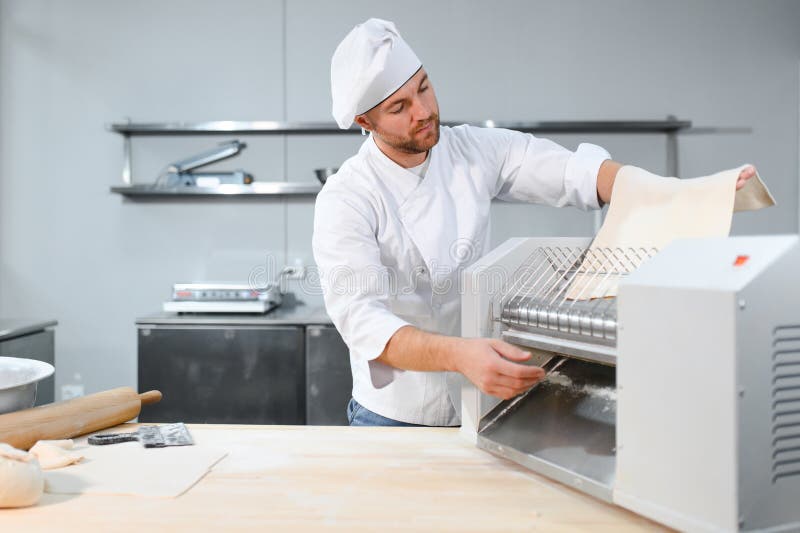 Concentrated at Work. Handsome Chef Rolling a Dough through Pasta ...