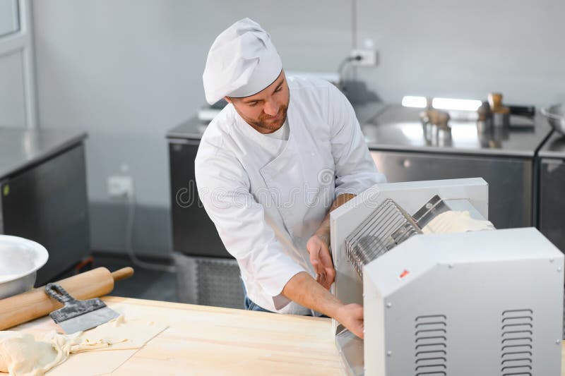 Concentrated at Work. Handsome Chef Rolling a Dough through Pasta ...