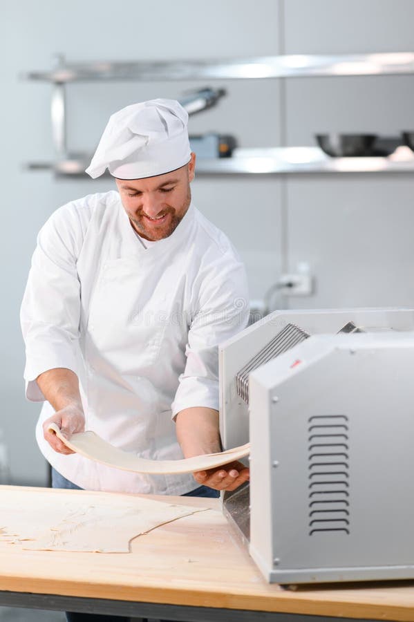 Concentrated at Work. Handsome Chef Rolling a Dough through Pasta ...