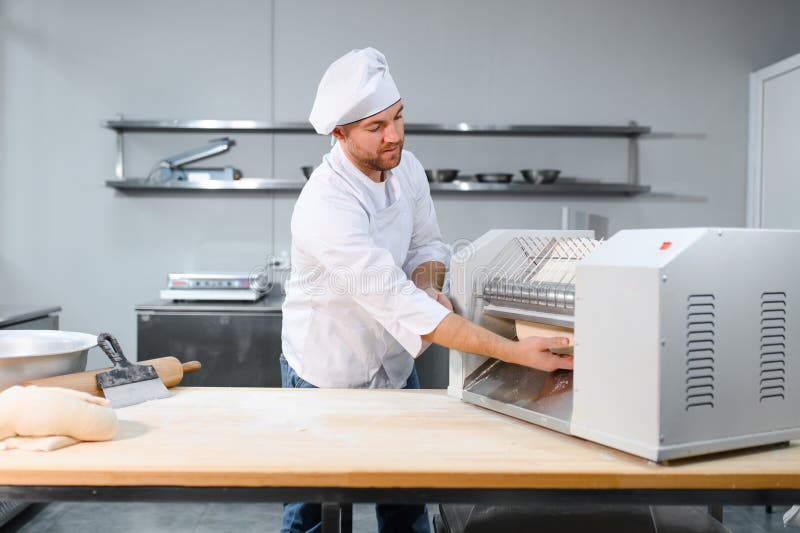 Concentrated at Work. Handsome Chef Rolling a Dough through Pasta ...