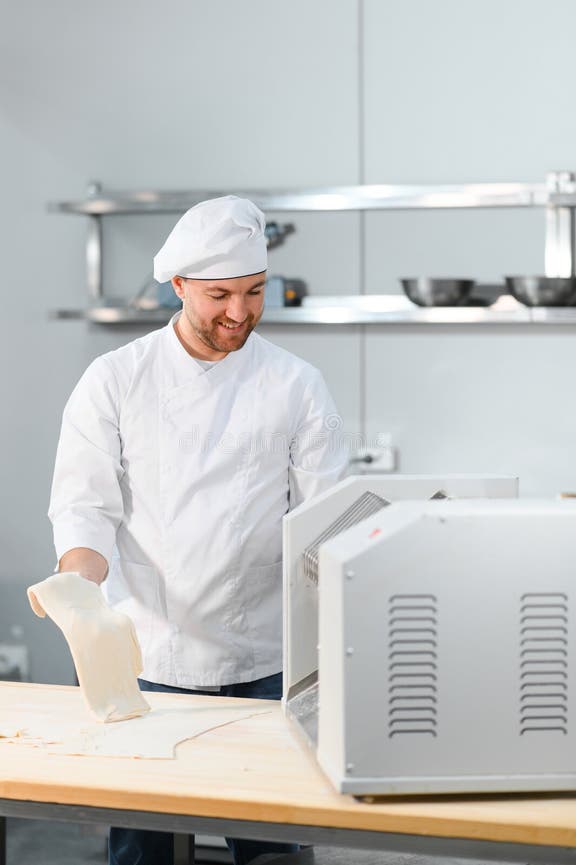 Concentrated at Work. Handsome Chef Rolling a Dough through Pasta ...