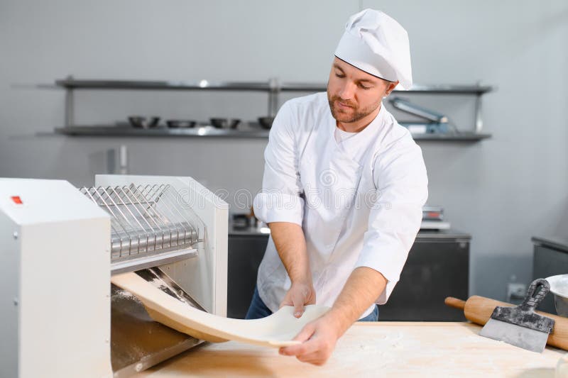 Concentrated at Work. Handsome Chef Rolling a Dough through Pasta ...