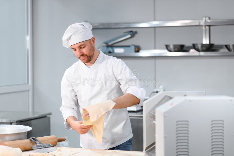 Concentrated at Work. Handsome Chef Rolling a Dough through Pasta ...