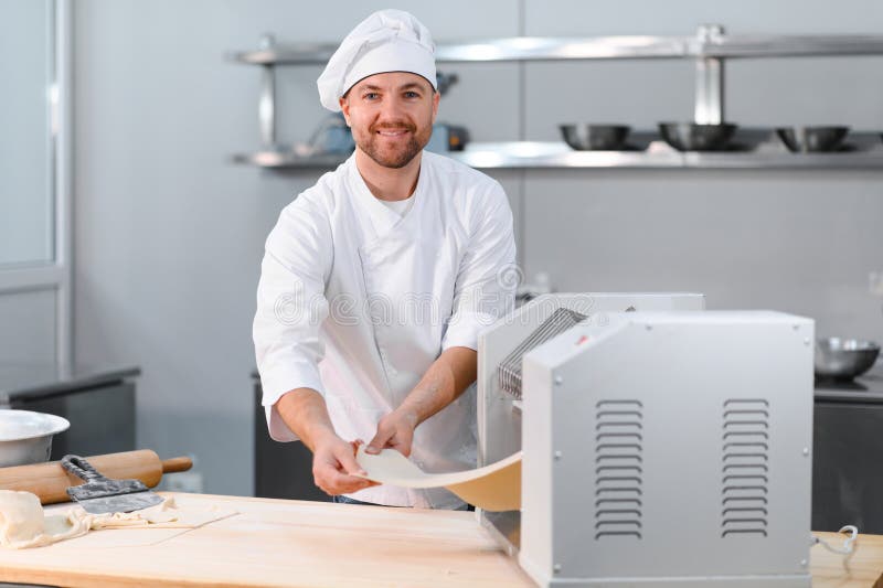 Concentrated at Work. Handsome Chef Rolling a Dough through Pasta ...