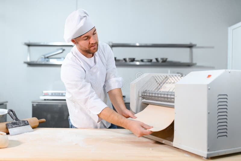 Concentrated at Work. Handsome Chef Rolling a Dough through Pasta ...