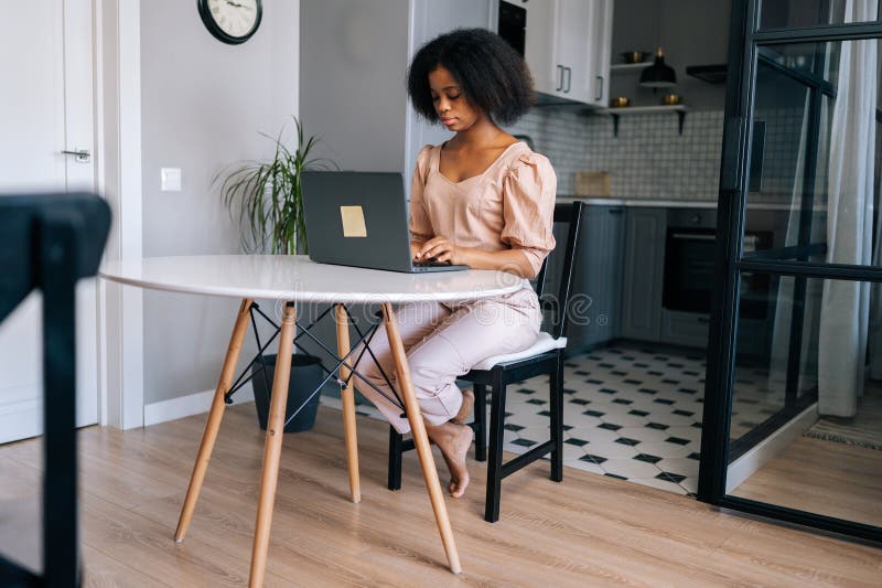 Concentrated Young African Female Student Sitting at Home Looking at Computer Screen Making ...