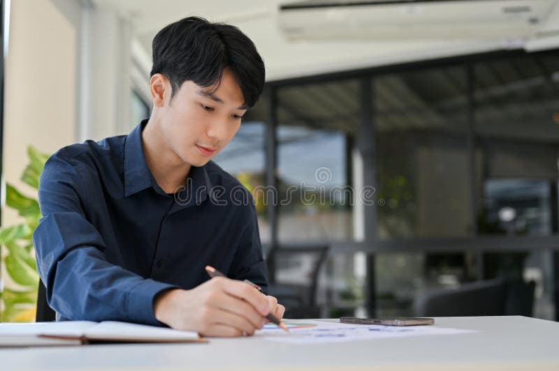 Concentrated Asian Male Financial Analyst Working on Financial Report ...