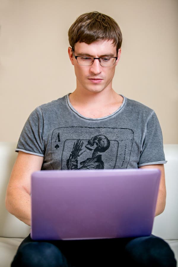 Concentrated Young Man with Glasses Working on a Laptop in a Home ...