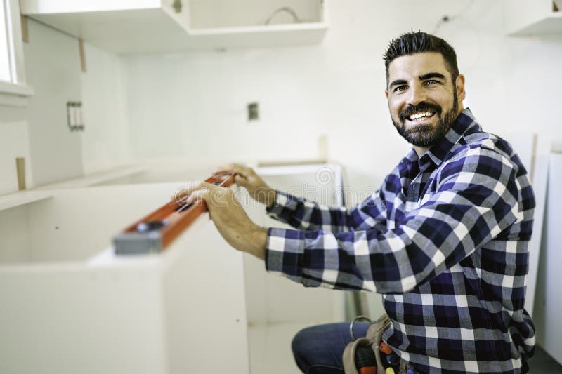 Concentrated Young Man Work with White Cabinet in the Kitchen with ...