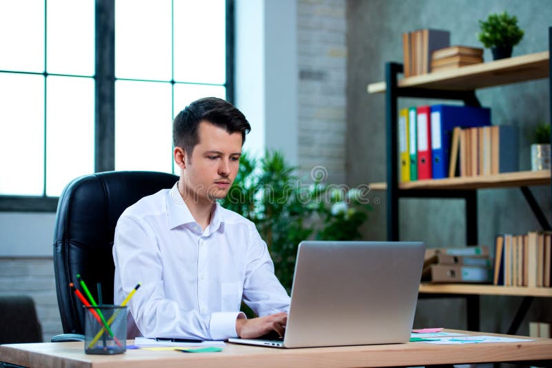 Concentrated Young Manager Man Sitting at Office Desk Working on Laptop ...