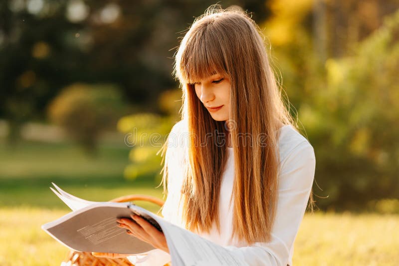 Concentrated Young Woman with Bangs is Reading a Book while Sitting in ...