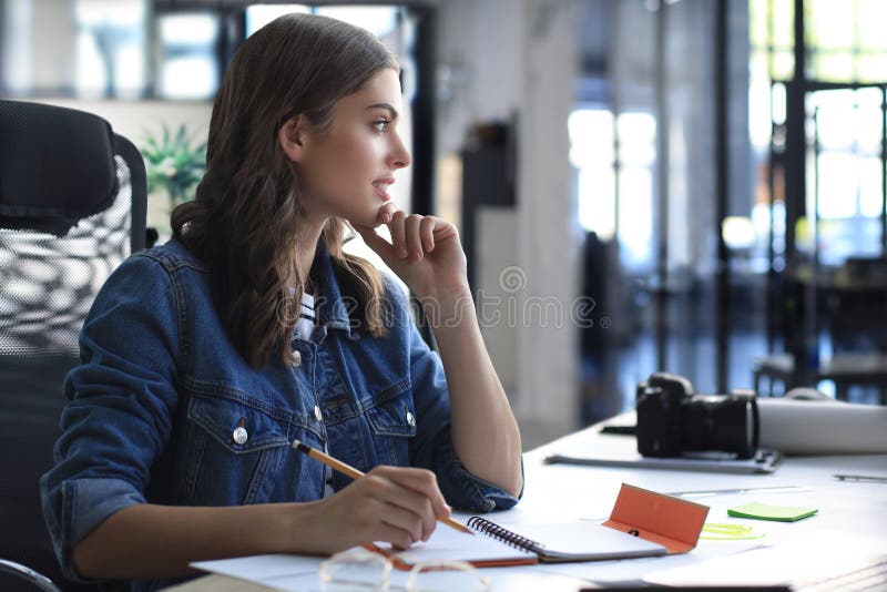 Concentrated Young Woman Writing Something Down while Working in the ...