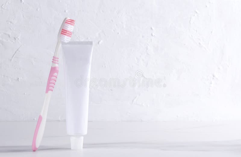 Tube of Toothpaste and Pink Toothbrush on the White Table Against White ...