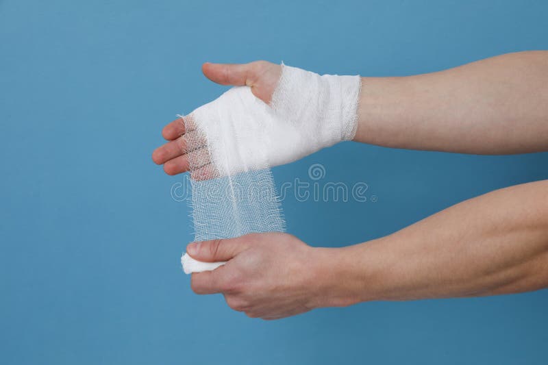 Concept of Help during an Injury, Man Wrapping Hand in Bandage on Blue ...