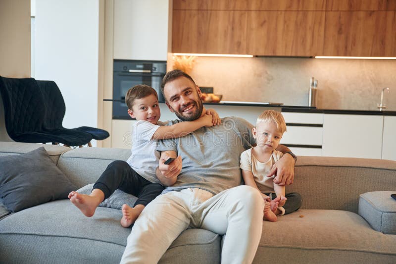 Conception of Relaxation. Father with Two Baby Boys is Sitting at Sofa ...