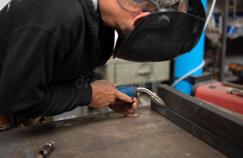 Performing a Weld: the Man in the Welding Mask is Positioned with the ...