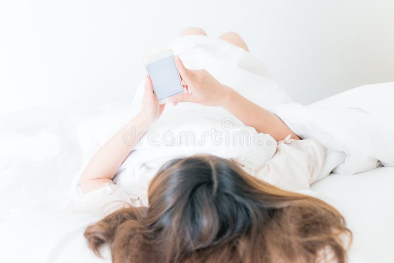 Asian Woman Lying on Bed and Using Her Smart Phone. Stock Image - Image ...