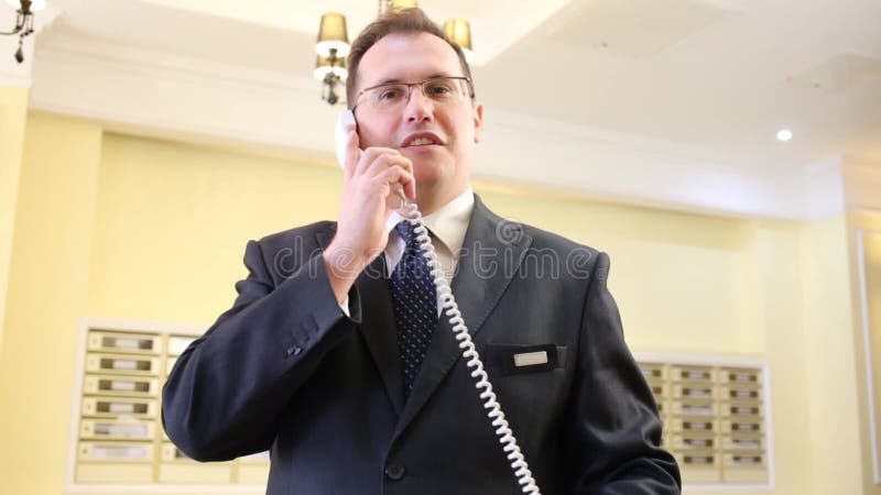 Concierge Talking on the Phone in Lobby and Hangs Stock Footage - Video ...
