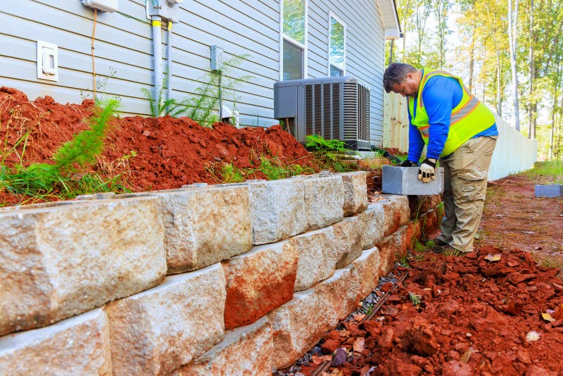 Concrete Blocks are Mounted To Retaining Wall by a Construction Worker ...