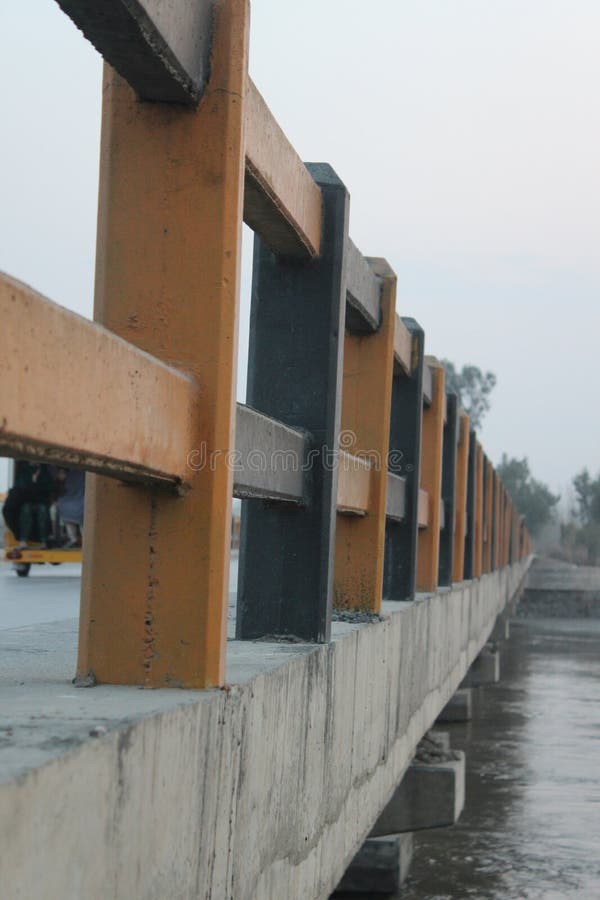 Concrete Bridge with Orange and Gray Railings Stretches Across a River ...