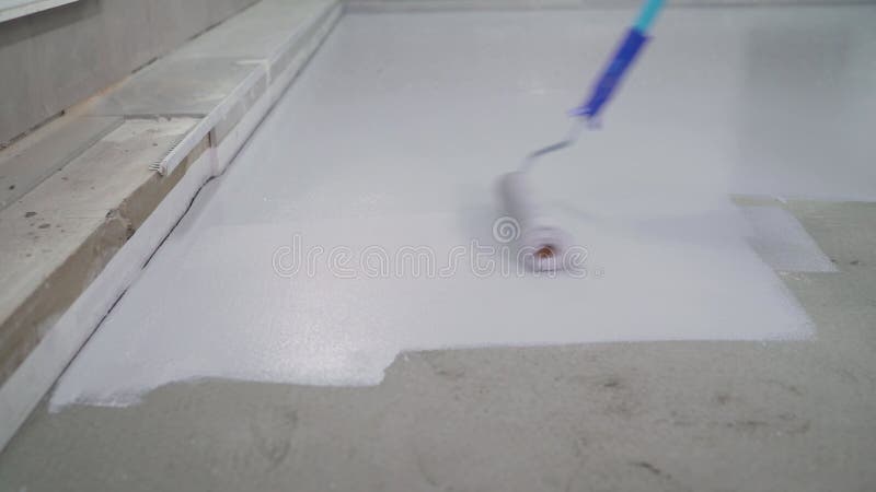 A Worker Paints the Concrete Floor with a Roller White. Concrete Floor ...