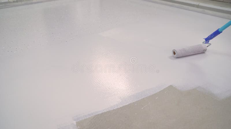 A Worker Paints the Concrete Floor with a Roller White. Concrete Floor ...