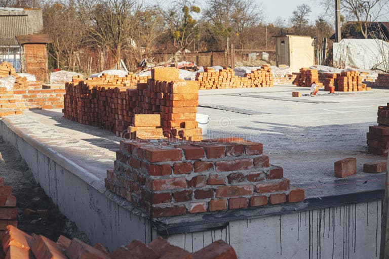 Concrete Foundation with Bricks for Laying. Stack of Red Bricks on ...
