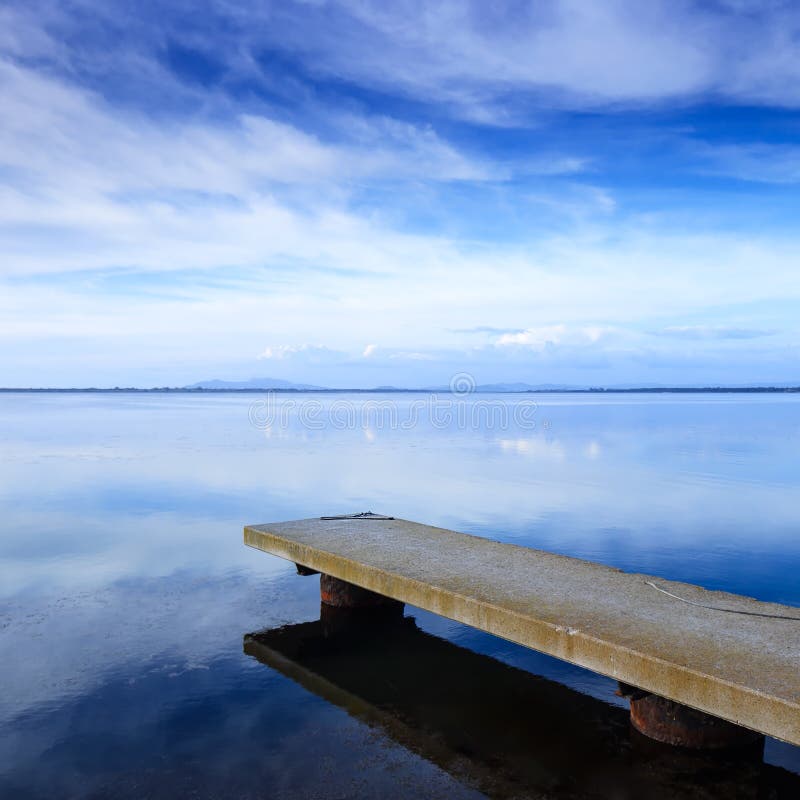 Concrete Pier or Jetty and on a Blue Lake and Sky Reflection on Water ...