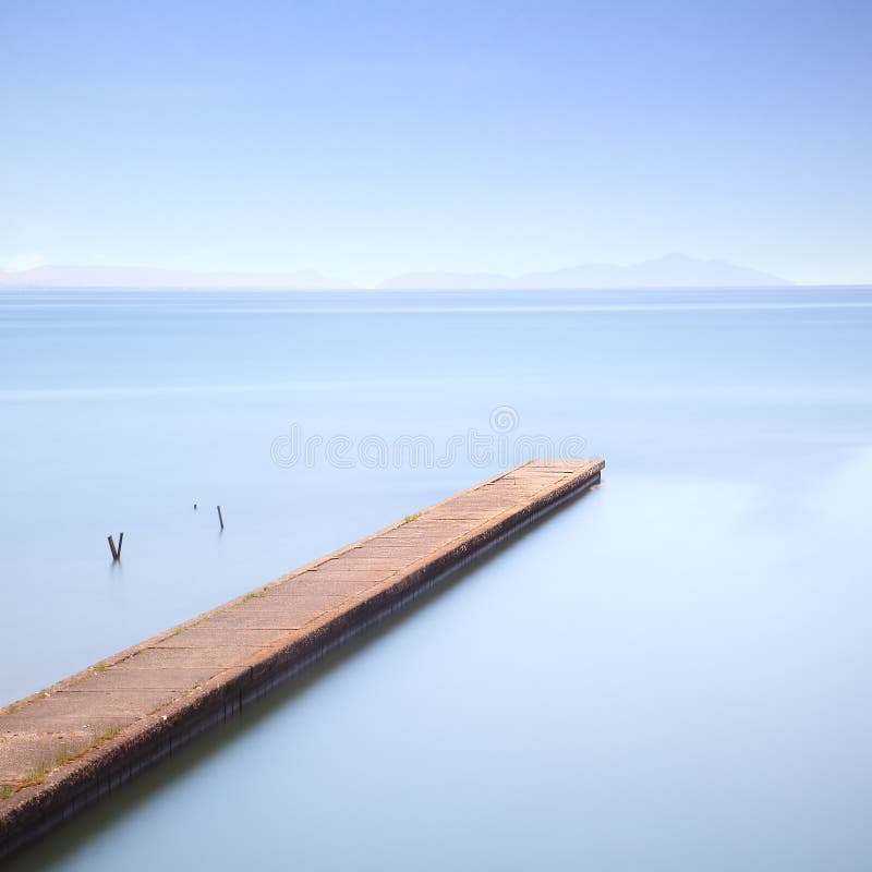 Concrete Pier or Jetty on a Blue Sea. Hills on Background Stock Image ...