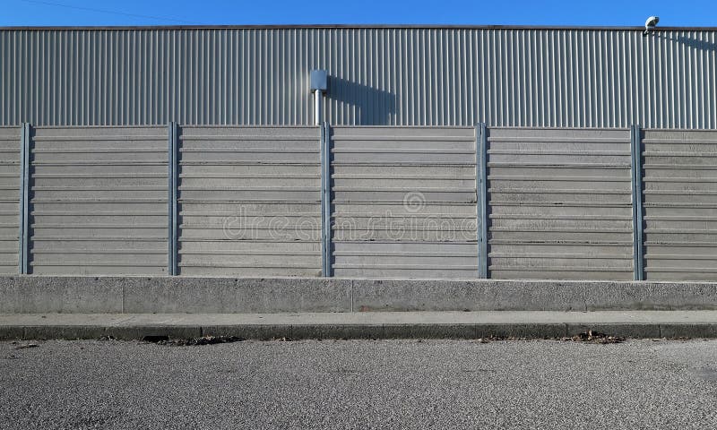Concrete Surrounding Wall, with a Gray Metallic Cladding Facade Behind ...