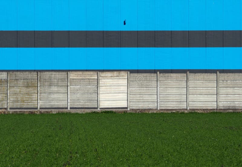 Concrete Surrounding Wall, a Light Blue and Gray Building with a Green ...