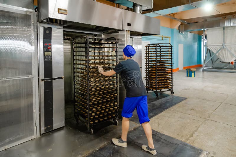 Confectionery Manufacturing. Baker Puts Cookies into Oven for Baking ...