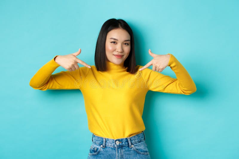 Confident Asian Woman In Stylish Sweater Pointing Fingers At Logo On