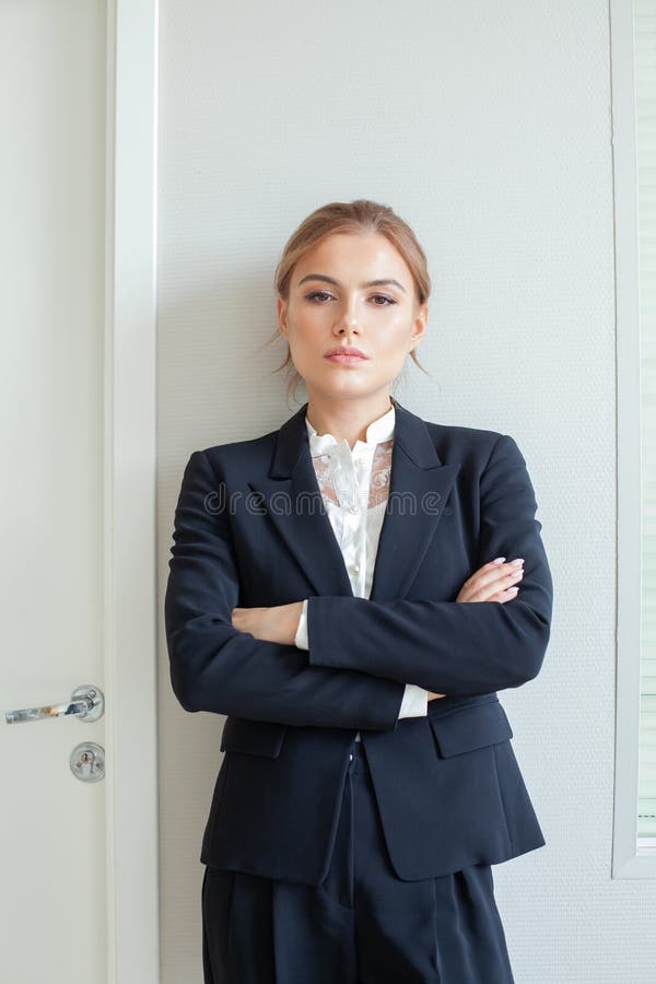 Confident Business Woman With Arms Crossed Standing Against White Wall
