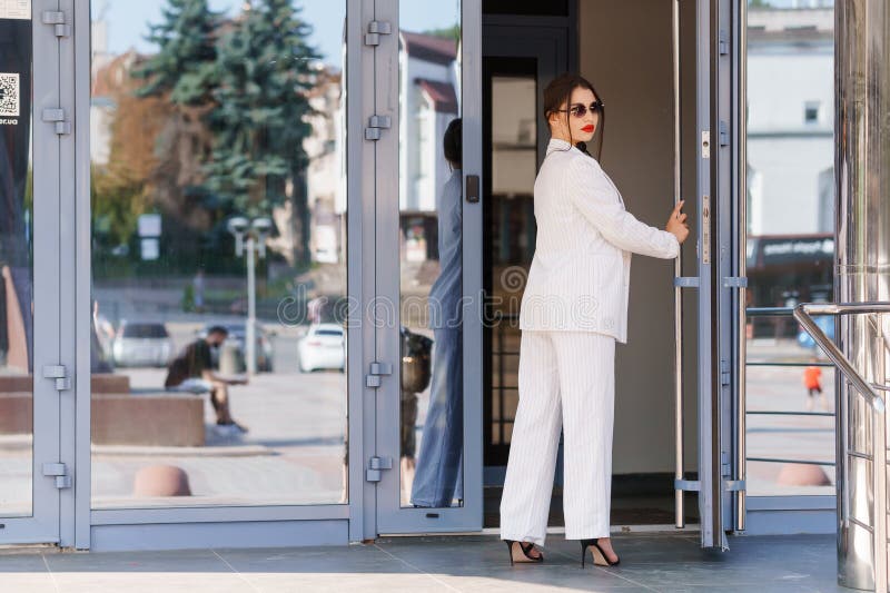 Confident Businesswoman in Striped Suit Elegantly Exiting Modern ...