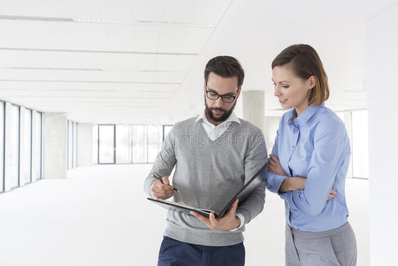 Confident Colleagues Discussing Over File in Empty Office Stock Photo ...